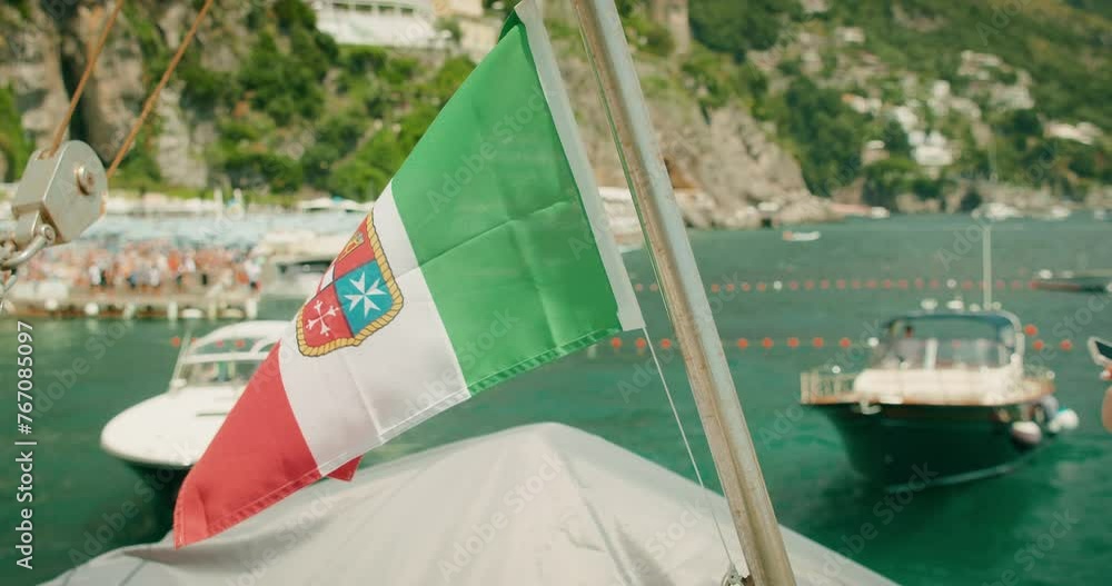 Italian flag fluttering on a boat with a blurred backdrop of the Amalfi ...