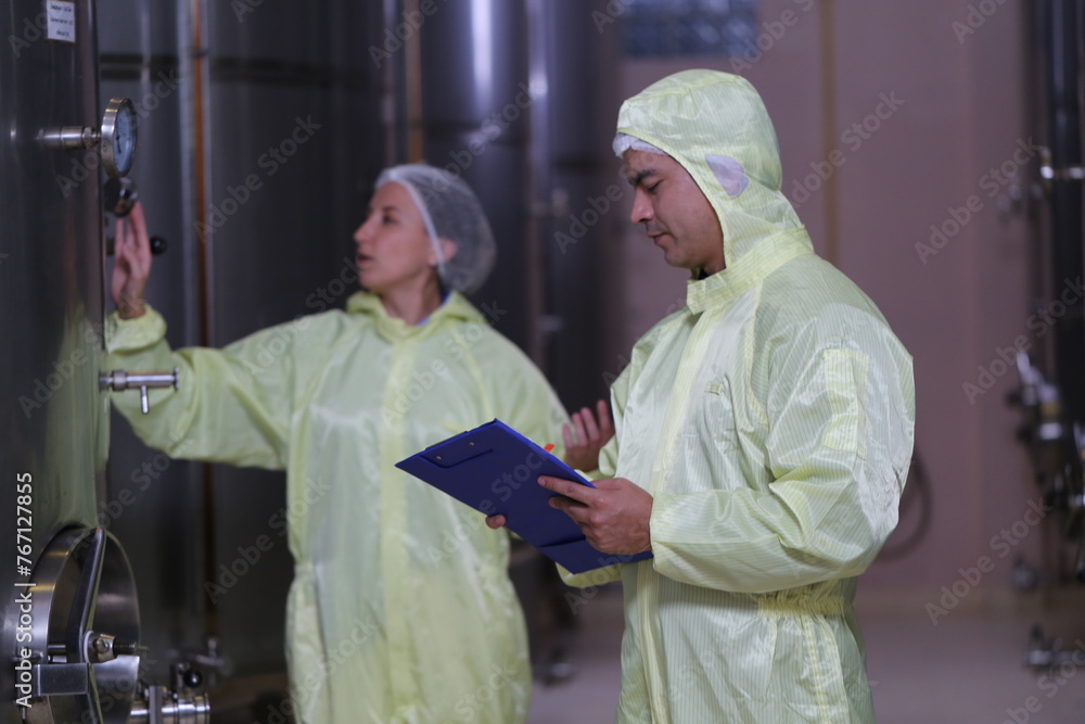 Winemaker woman and business owner wearing a sterile suit working and ...