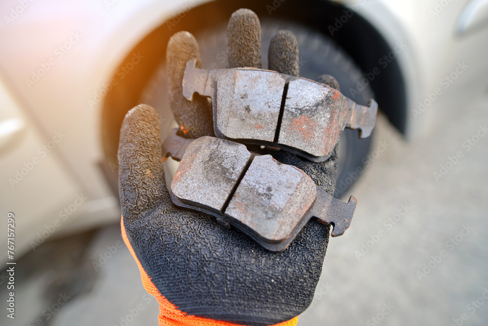 Mechanic holds bad brake pads in hand, replacing worn uneven defective ...