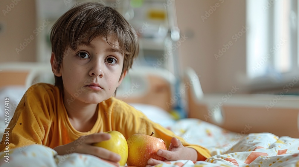 portrait of a young patient in a hospital bed eating an apple with a ...