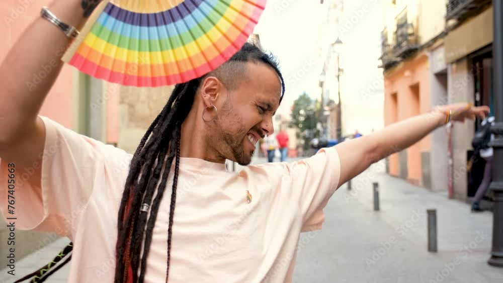 Gay man with dreadlocks smiling and dancing holding a rainbow fan ...