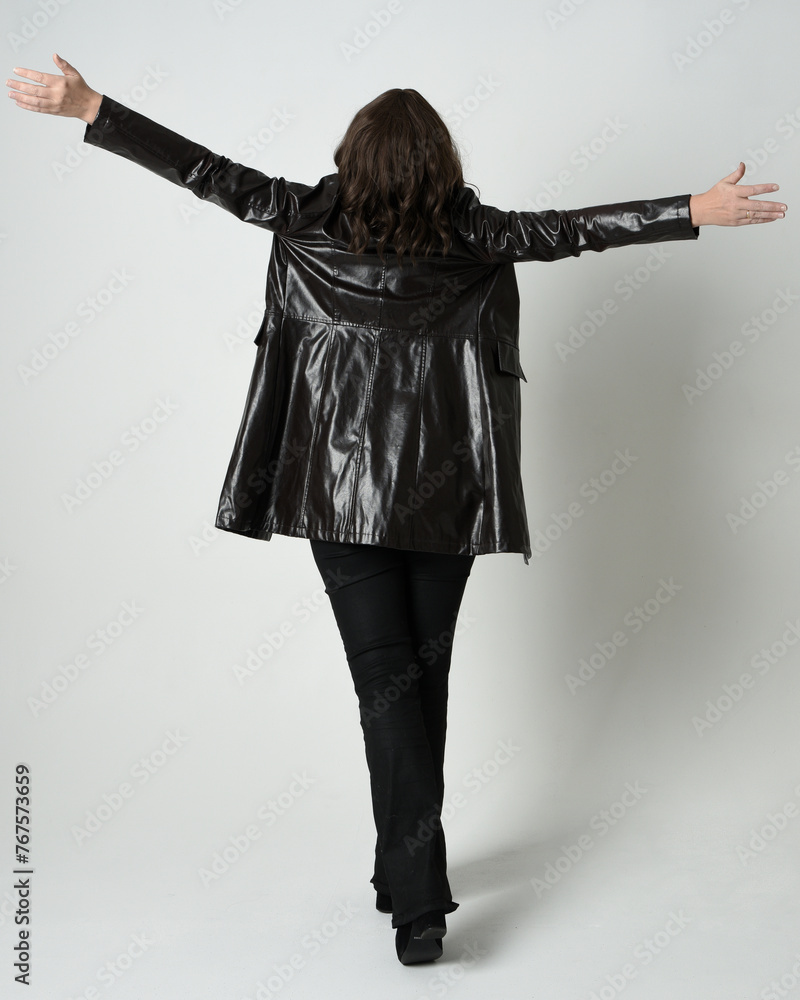 Full length portrait of brunette woman wearing long leather trench coat ...