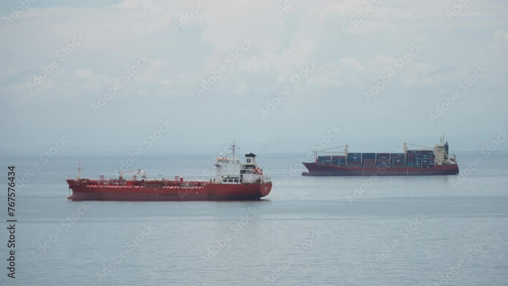 Chartered cargo ships sit at anchor in calm sea bay, waiting to unload ...