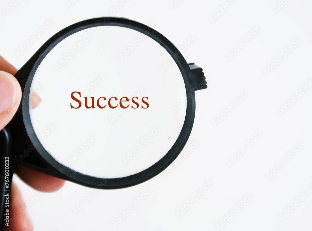 Hand holding magnifying glass focus on the text written SUCCESS ...