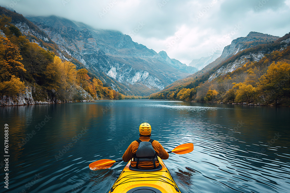 back of kayaker kayaking on lake with a landscape of mountain and ...