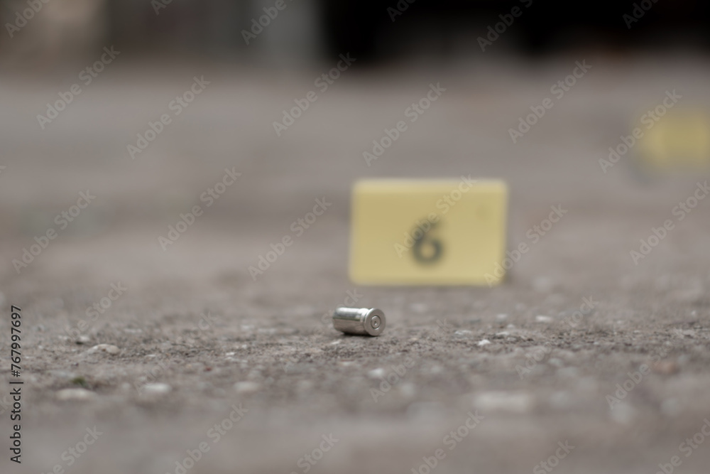 Pistol bullet shell on cement floor with blurred number six yellow ...