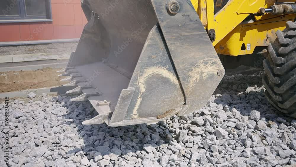 An automotive tire bulldozer is spreading gravel on a construction site ...