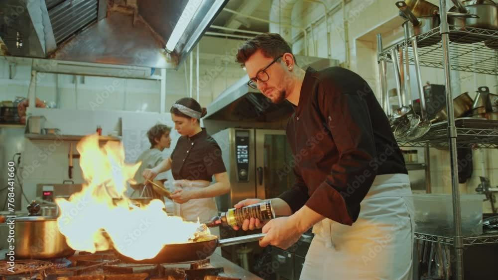 Skilled chef using blow torch while cooking food in pan in burning fire ...