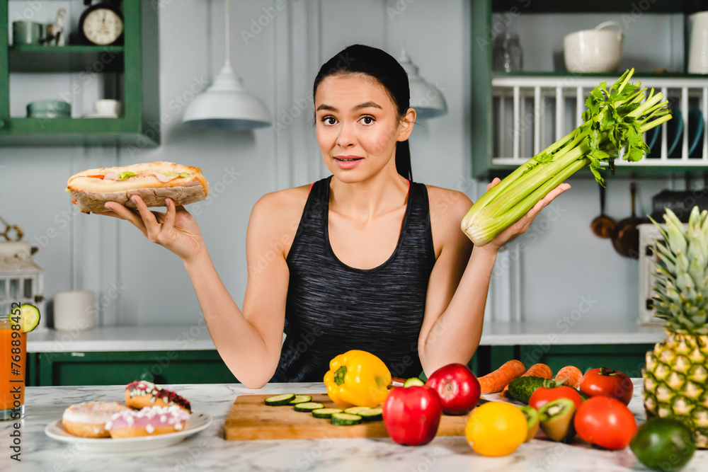 Young fit caucasian woman choosing between healthy and unhealthy food ...
