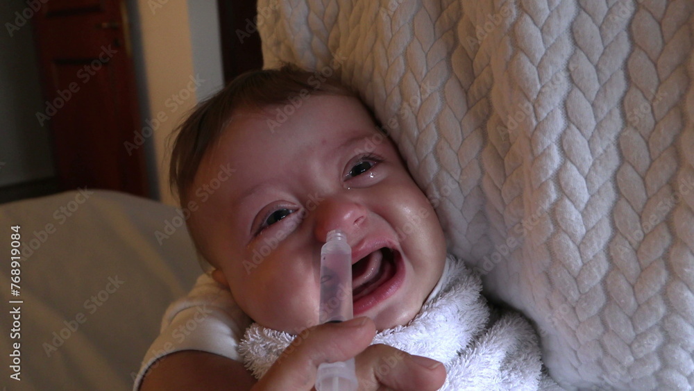 Removing baby mucus by decongesting nose with saline syringe. Mother ...