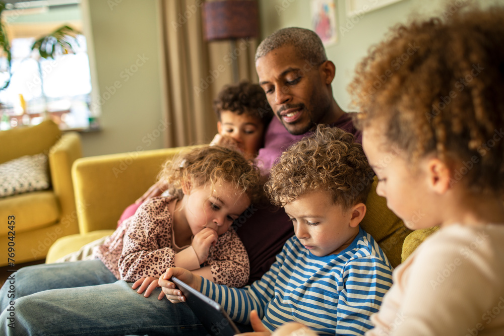 Father using the tablet with his kids on the couch at home Stock Photo ...