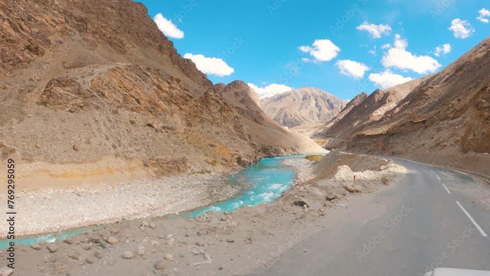 4K shot of blue coloured Zanskar river flowing besides the Himalayan ...