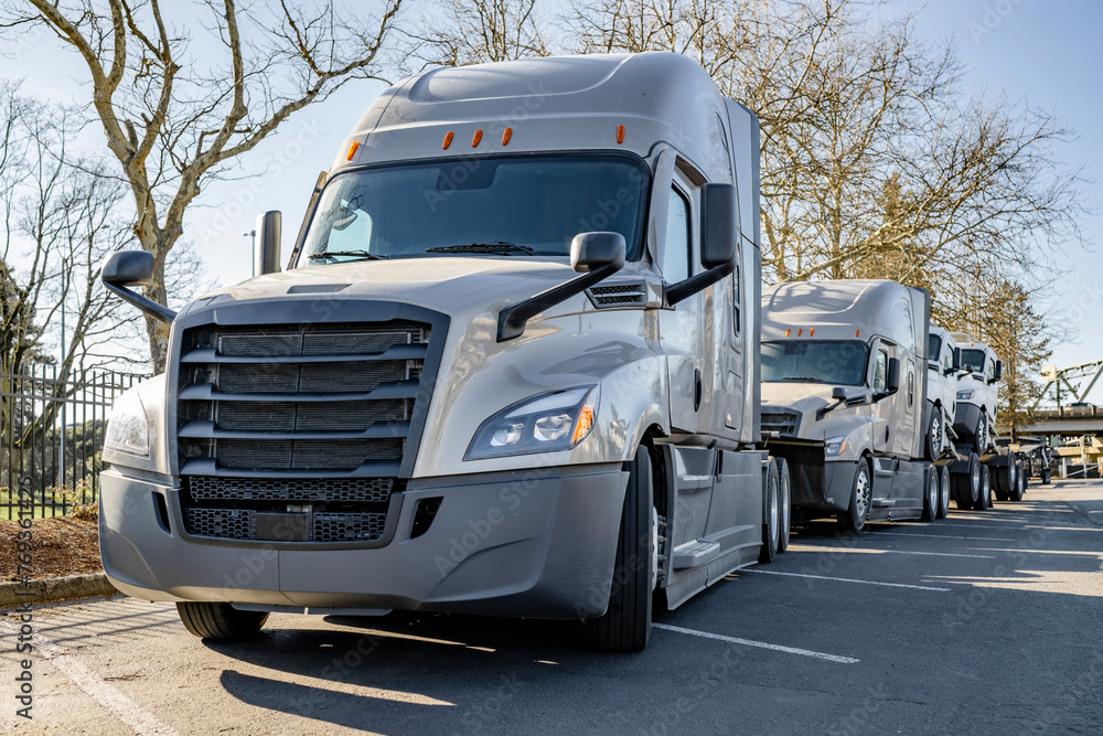 Beige big rig semi truck tractor towing other semi trucks tractors ...