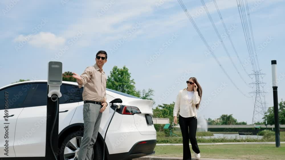 Slow motion couple recharge EV car battery at charging station ...