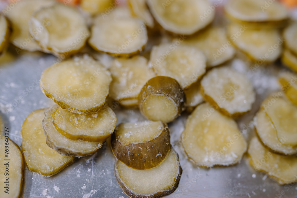Sliced and frozen pickles are scattered on a tray, showing icy crystals ...