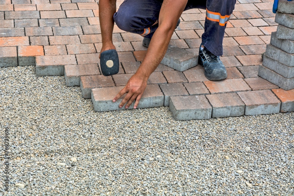 two workers putting the bricks on the ground in front of a brick ...