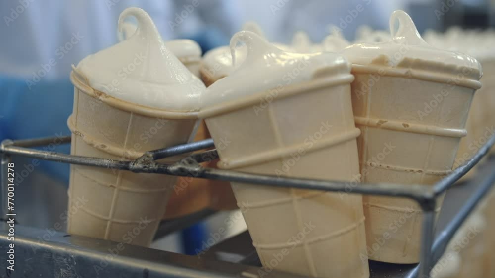 Ice cream in waffle cups are produced at industrial milk plant. Worker ...