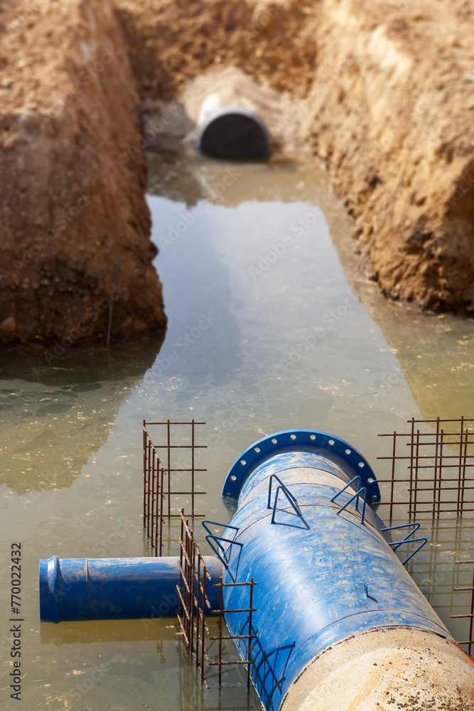 construction workers install pipes and valves for irrigation in fields ...