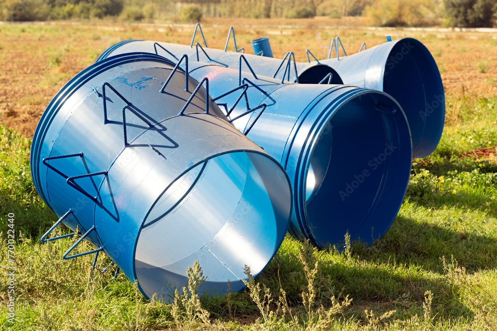 construction workers install pipes and valves for irrigation in fields ...