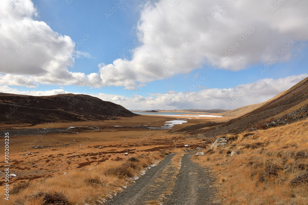 A narrow field road winding along the slopes at the foot of the ...