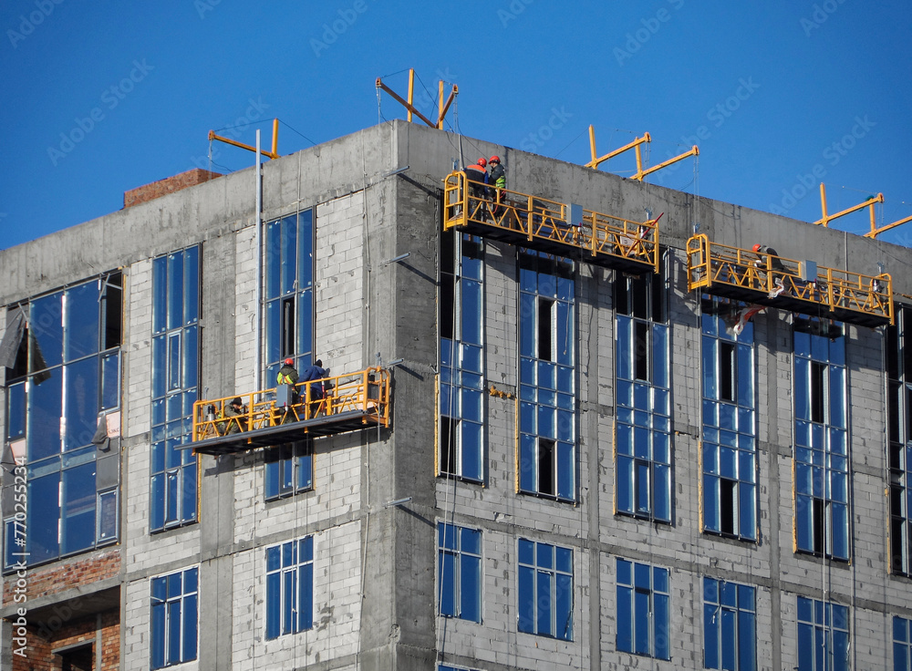 Workers team on construction cradle. The process of insulating external ...