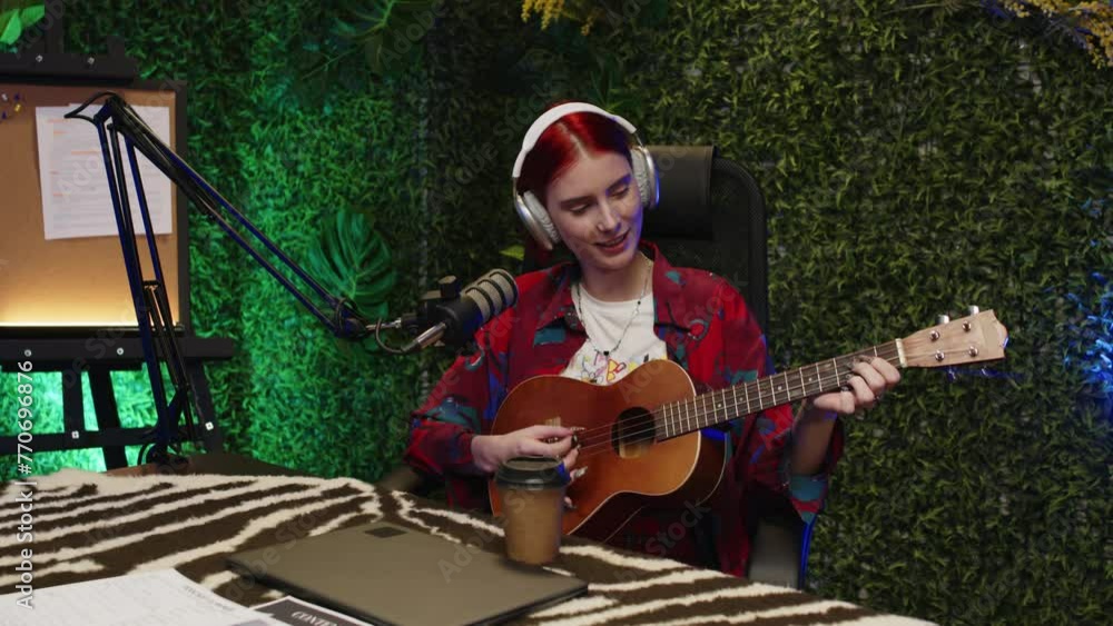 Young gen Z female musician in headphones playing guitar and singing in ...