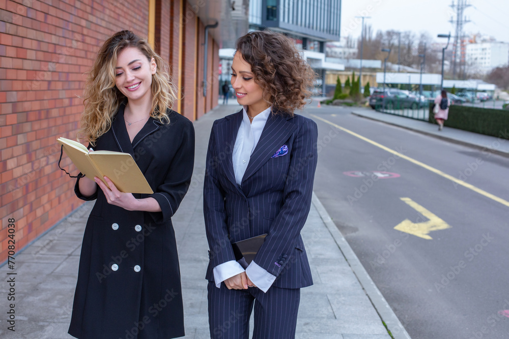 Two successful business women are talking in the city in front of a ...