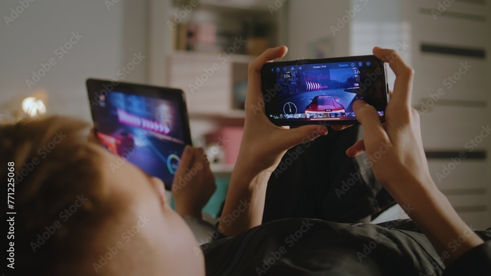 Teenagers lie on bed in their room and play video games on digital ...