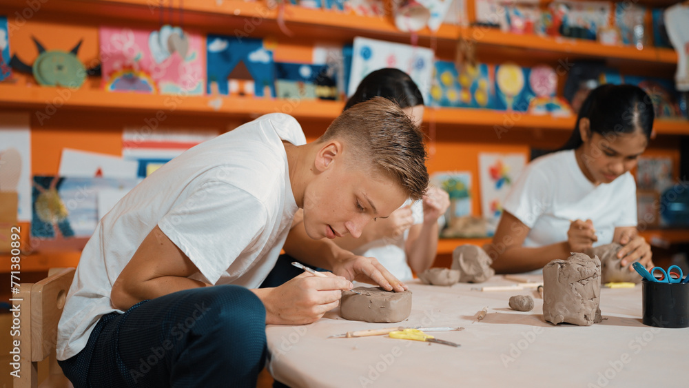 Highschool teenager using carving tool working at clay at pottery ...