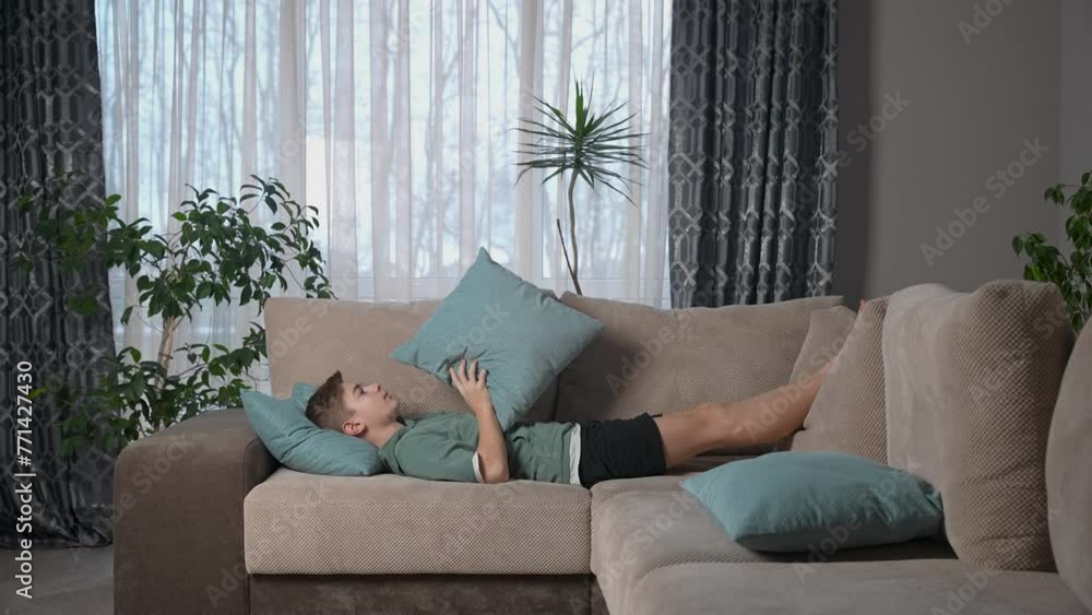 Smiling relaxed boy lying on sofa, enjoying rest. Happy positive kid ...