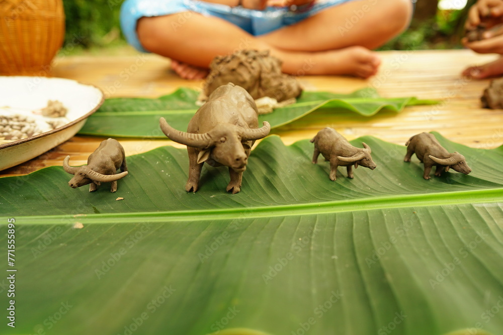 Take clay and make large and small buffalo shapes and place them on ...