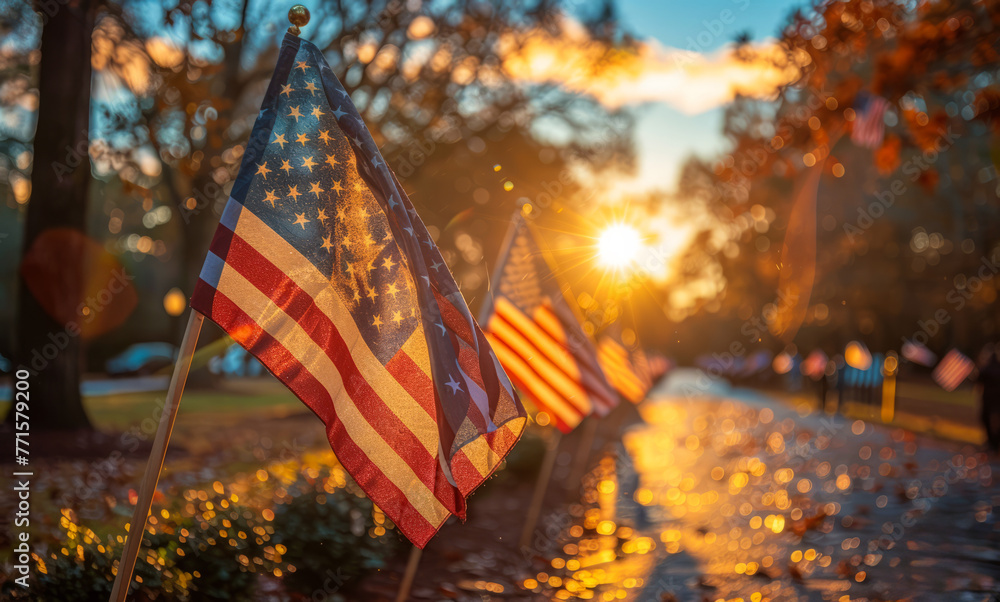 A row of American flags are displayed on a sidewalk in front of a tree ...