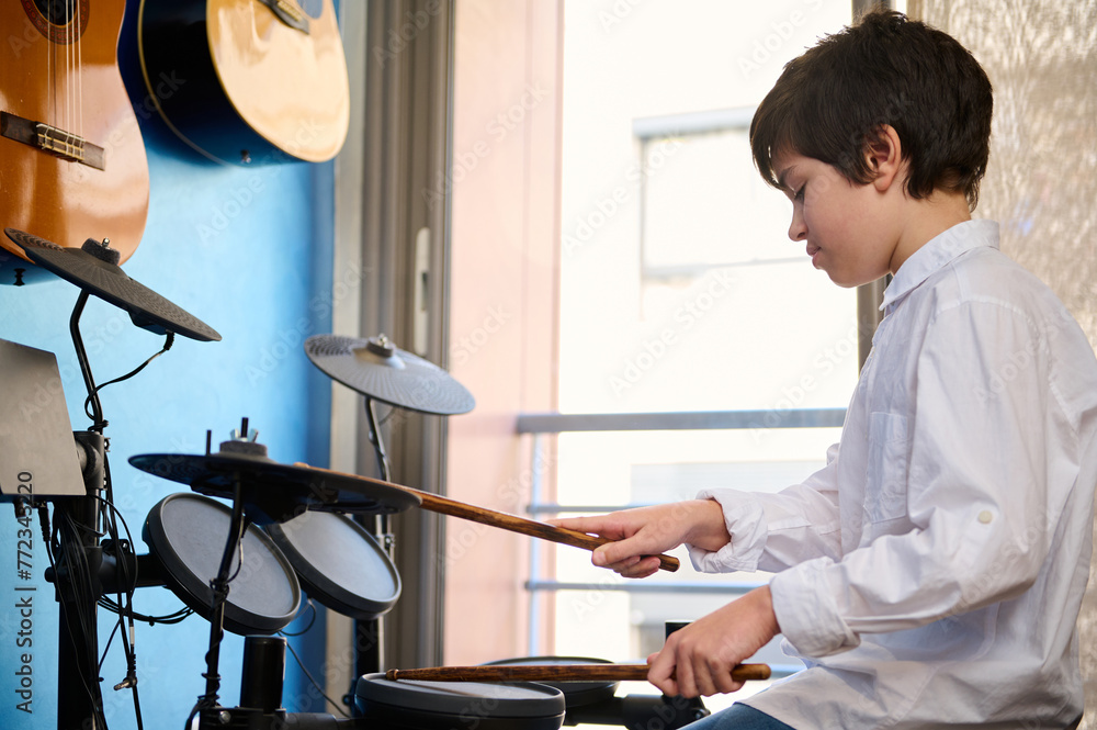 Side portrait of a Caucasian handsome teenage boy musician drummer ...