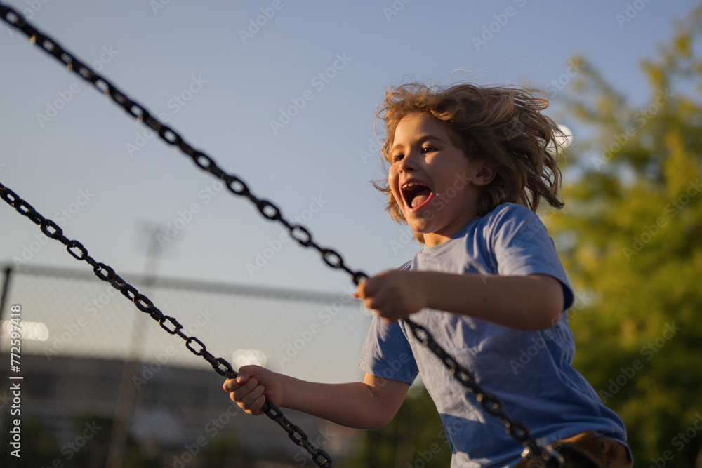 Excited child swinging on chain swing on city kids playground. Swing ride. Cute child having fun ...