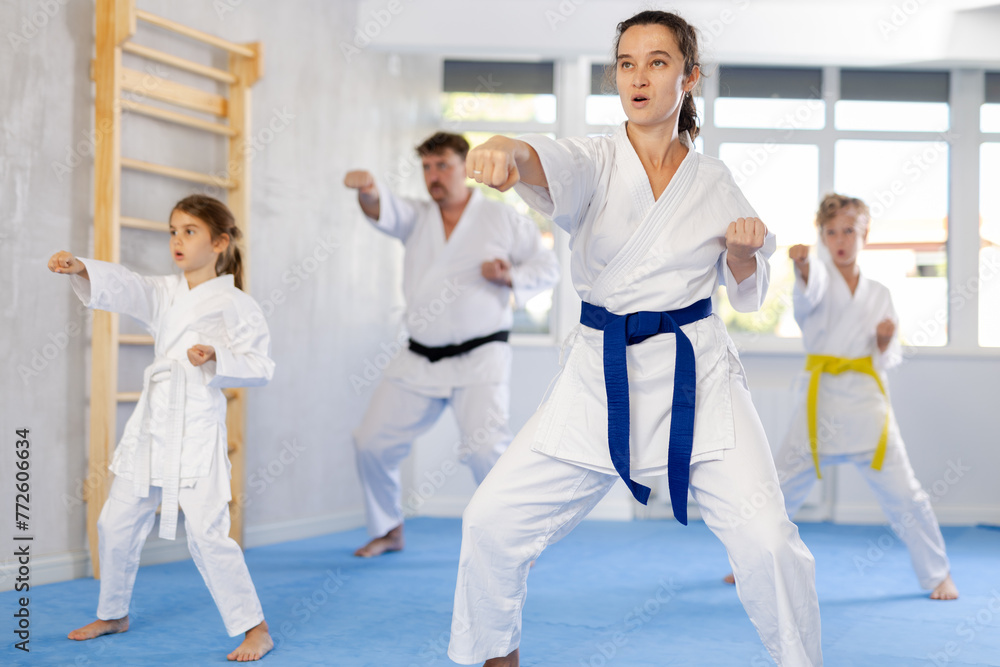 Concentrated woman practicing kata routine with husband and tween ...