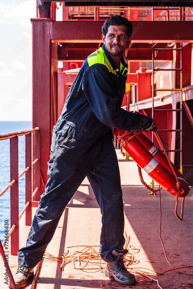 Young seafarer with lifebuoy on the cargo ship - he is throwing ...