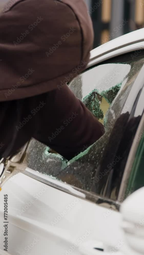 Crime in hood breaks car window bright thief vertical video. Person ...