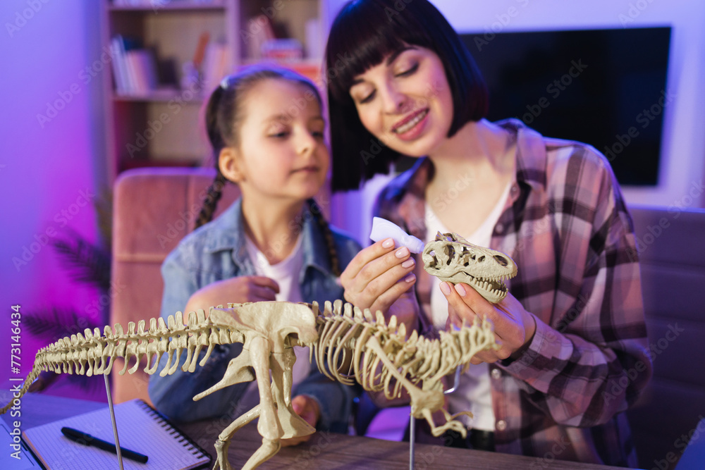 Caring woman and small kid girl improving knowledge at evening home. Caucasian mother assemble ...