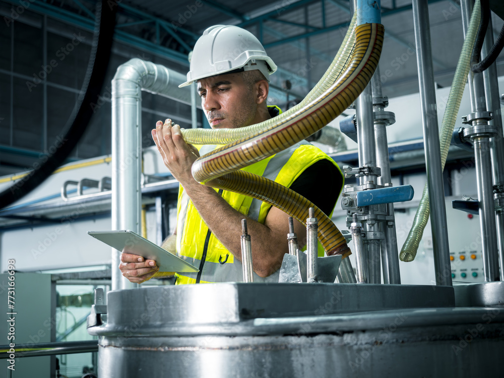 Engineers at a beverage factory in uniforms with helmets are inspecting ...