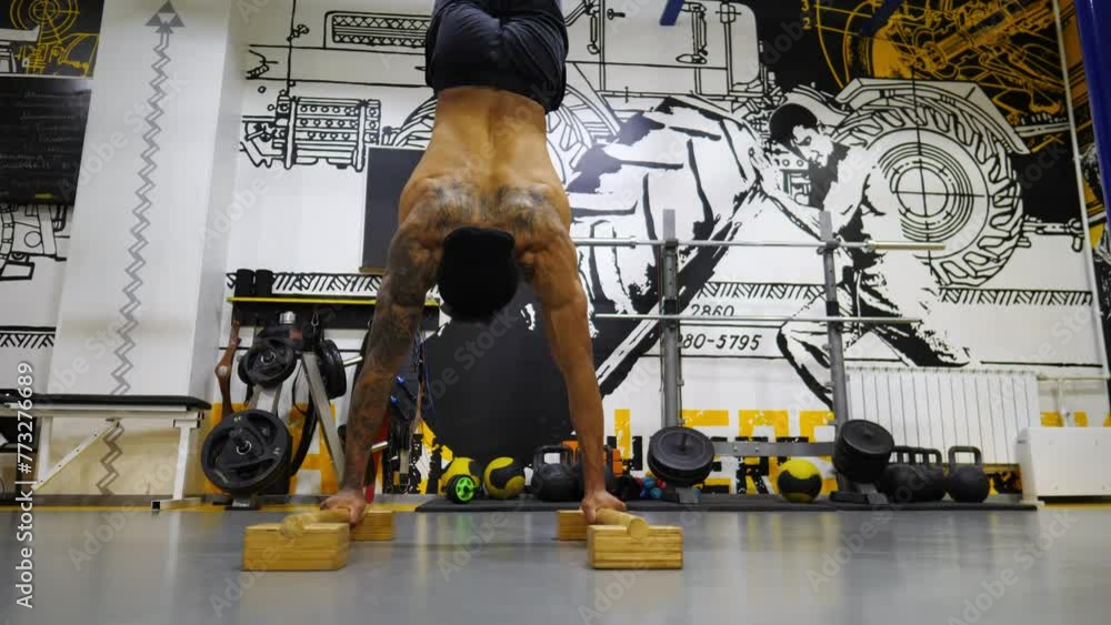 Young afro american sportsman trying to do push ups in handstand on ...