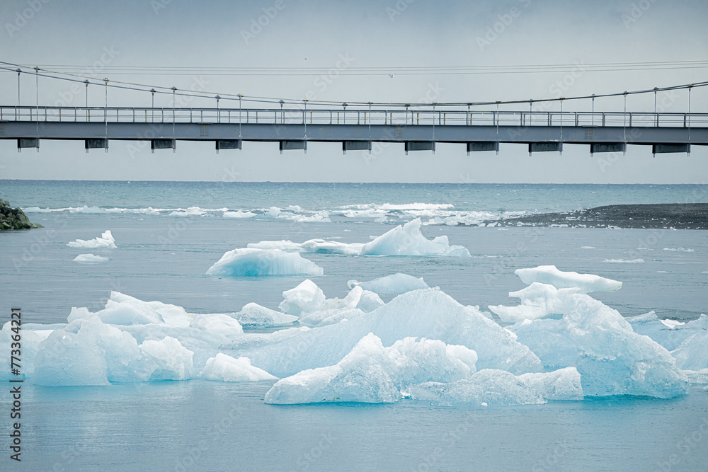 Icebergs can be seen floating in the iceberg lagoon under a bridge ...