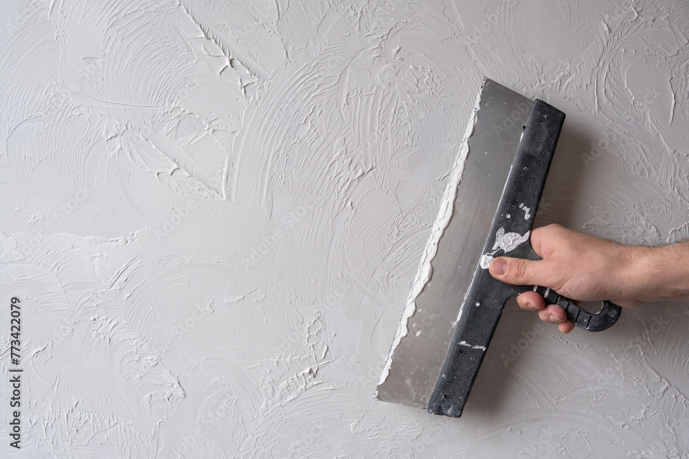 Applying decorative putty. White abstract texture of surface covered ...