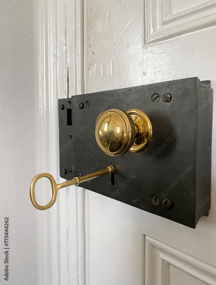 Ancient door lock with old metal key in the keyhole. Golden door handle ...