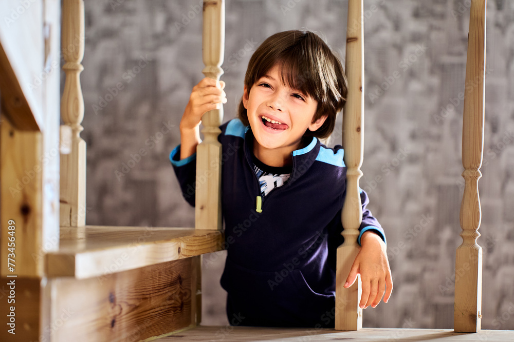 Seven year old boy stuck out his tongue while making faces on wooden ...