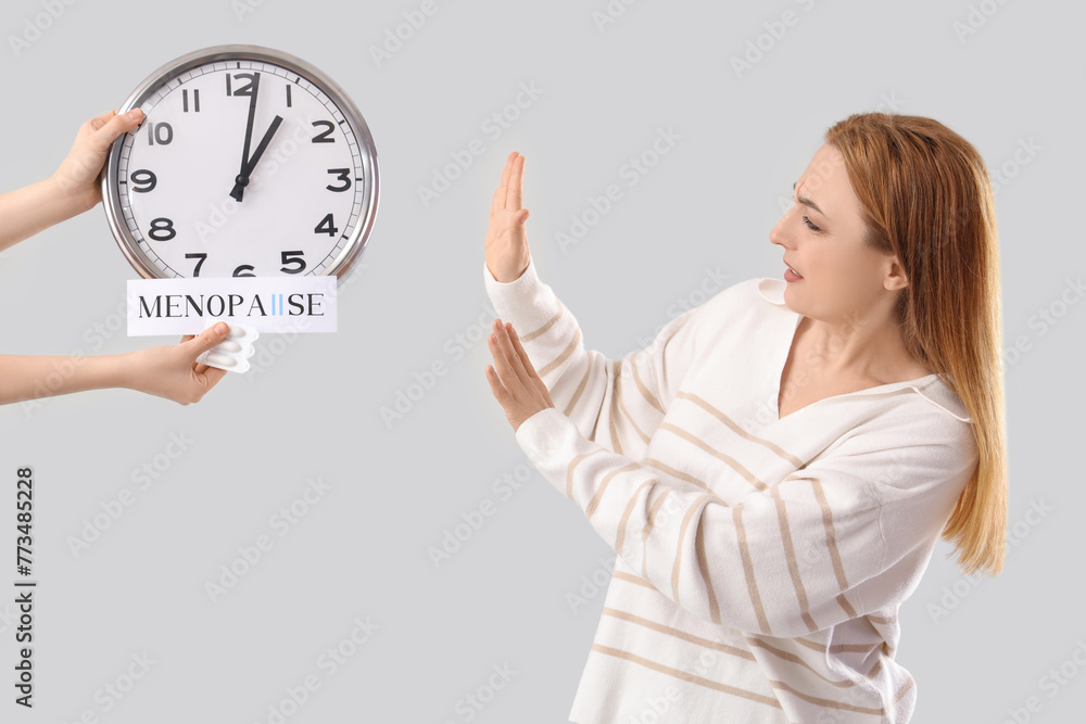 Mature woman rejecting clock and suppositories on light background ...