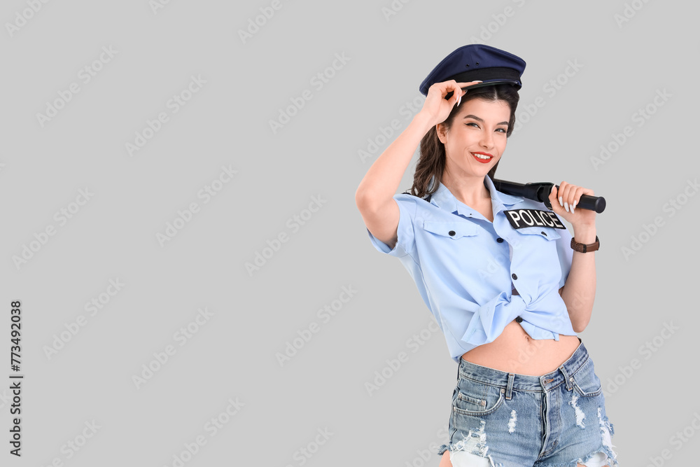 Beautiful pin-up police officer with baton on grey background Stock Photo | Adobe Stock