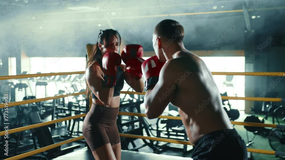 A focused female boxer and her trainer engage in a rigorous boxing ...