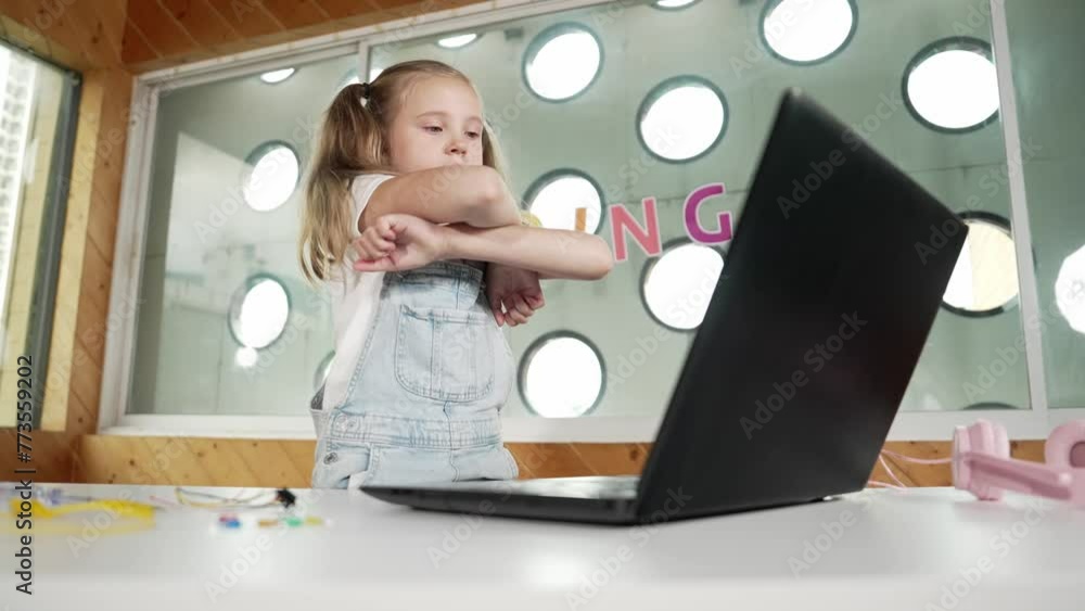 Cute girl using laptop programing software while looking at camera with ...