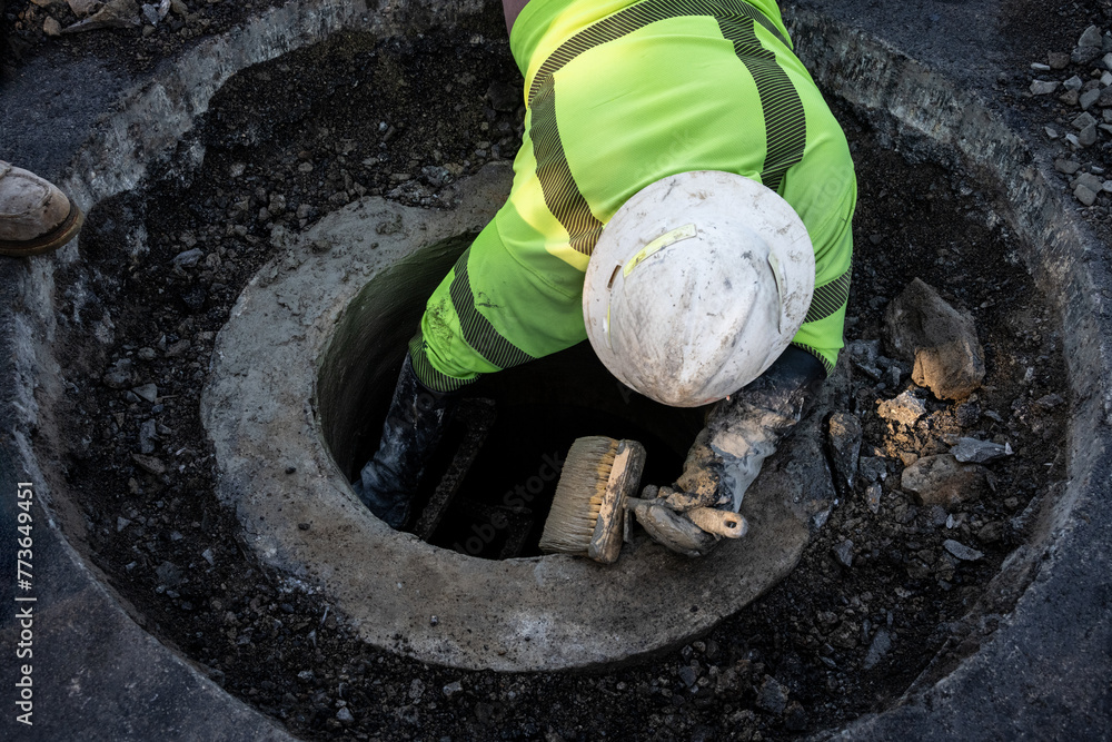 Construction worker in safety gear laying on street working to reseal ...