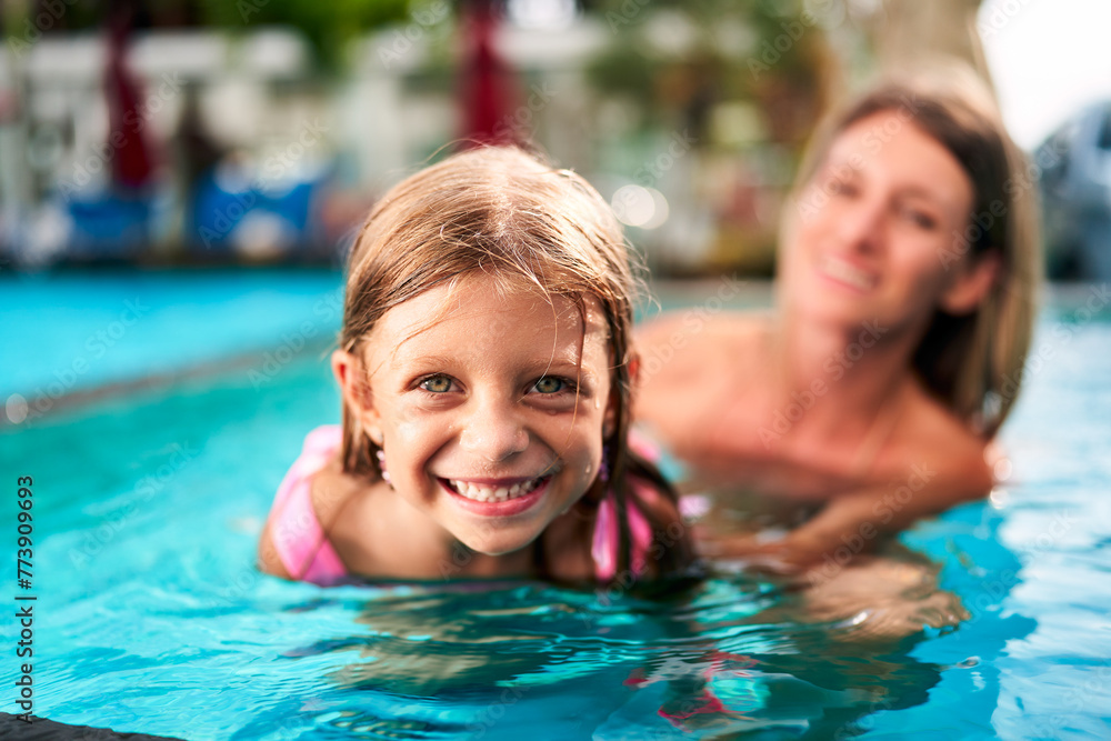 Smiling young girl with swim cap learns swimming in pool, guided by ...